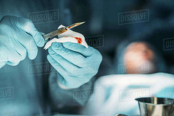 Cropped image of surgeon cleaning scalpel from blood - Royalty-free ...
