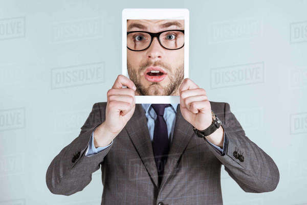 Young businessman holding digital tablet with his face on screen ...