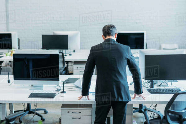 Back view of businessman standing at workplace in office - Royalty-free ...