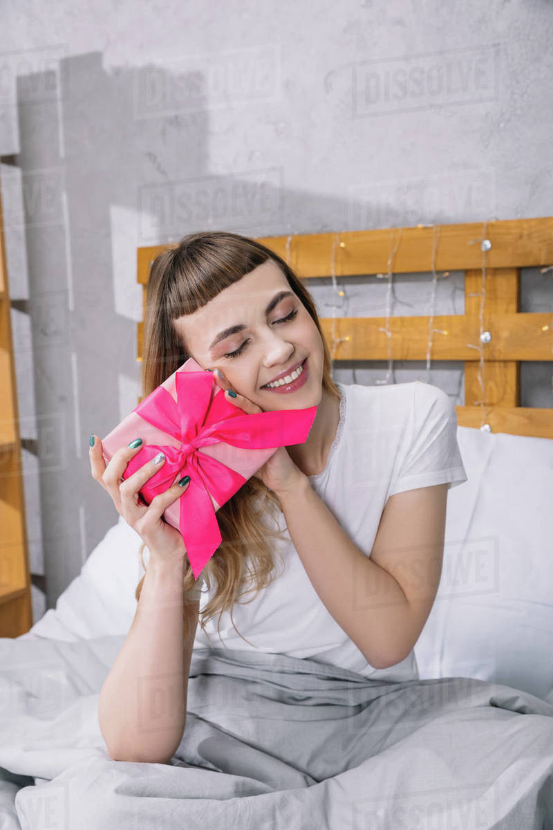 Smiling girl touching gift box with face - Royalty-free Stock Photo ...