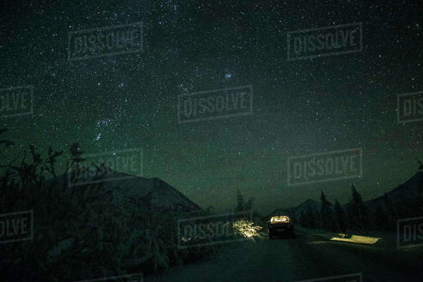 Car standing on winter road and beautiful starry sky in mountains at ...