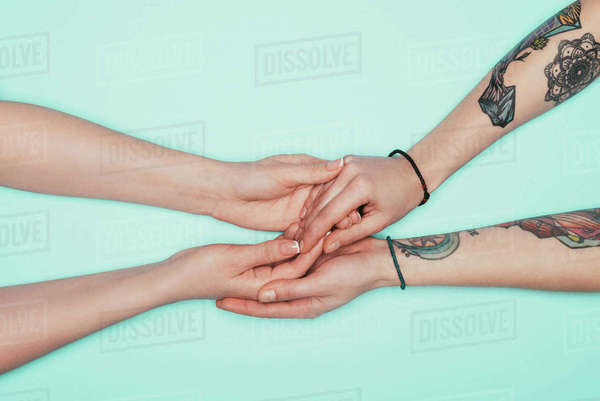 Cropped shot of sensual women holding hands of each other isolated on ...