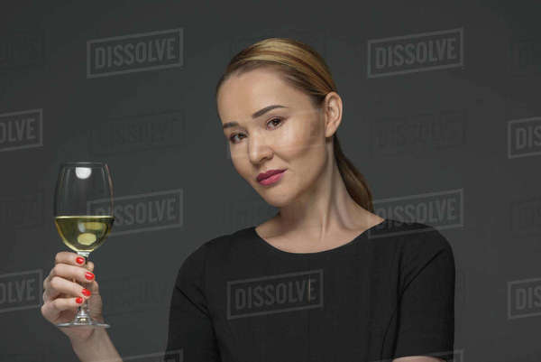Smiling Kazakh woman holding glass of wine and looking at camera ...