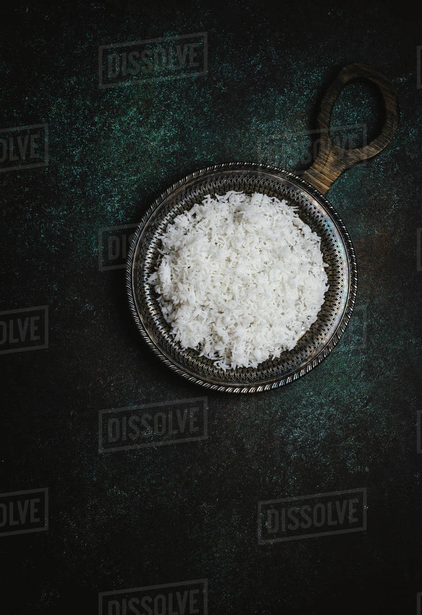 Top view of cooked white rice on rustic metal tray on dark table ...