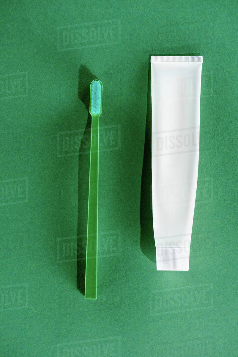 Top view of toothbrush and tube of toothpaste, on green - Royalty-free ...