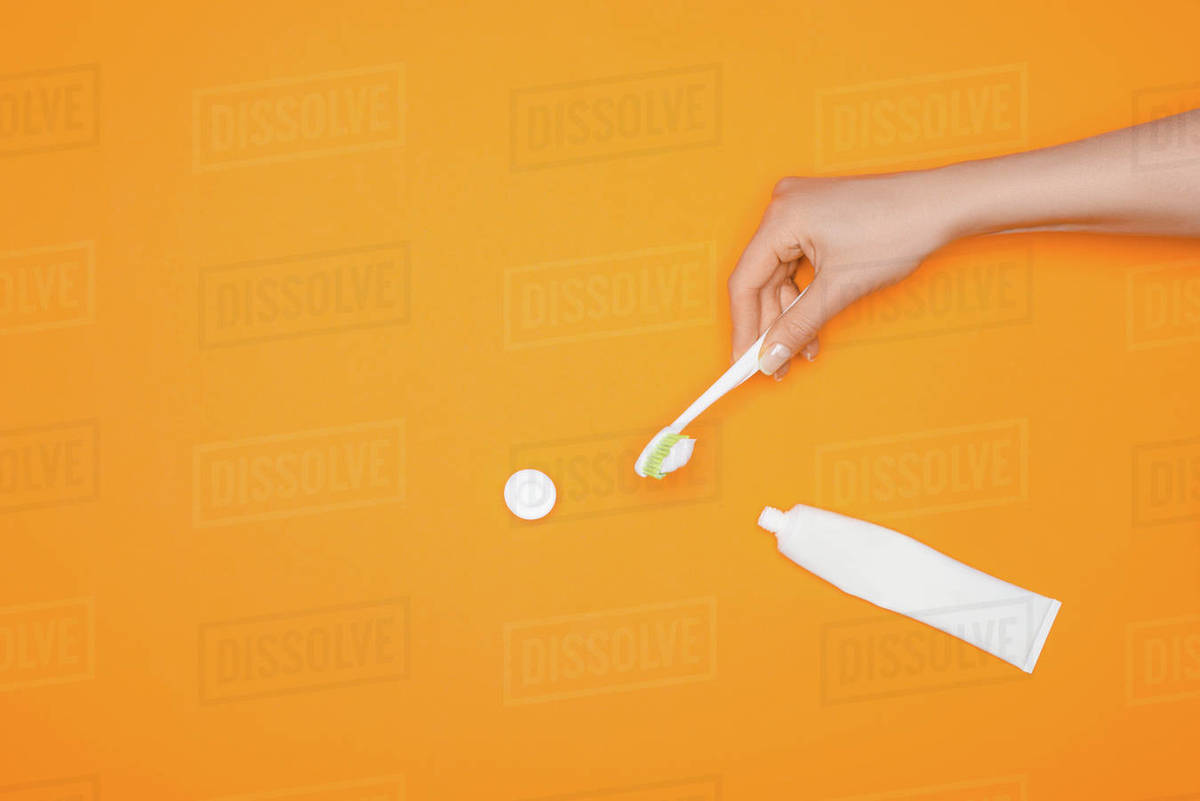 Cropped view of woman holding toothbrush and tube of toothpaste ...