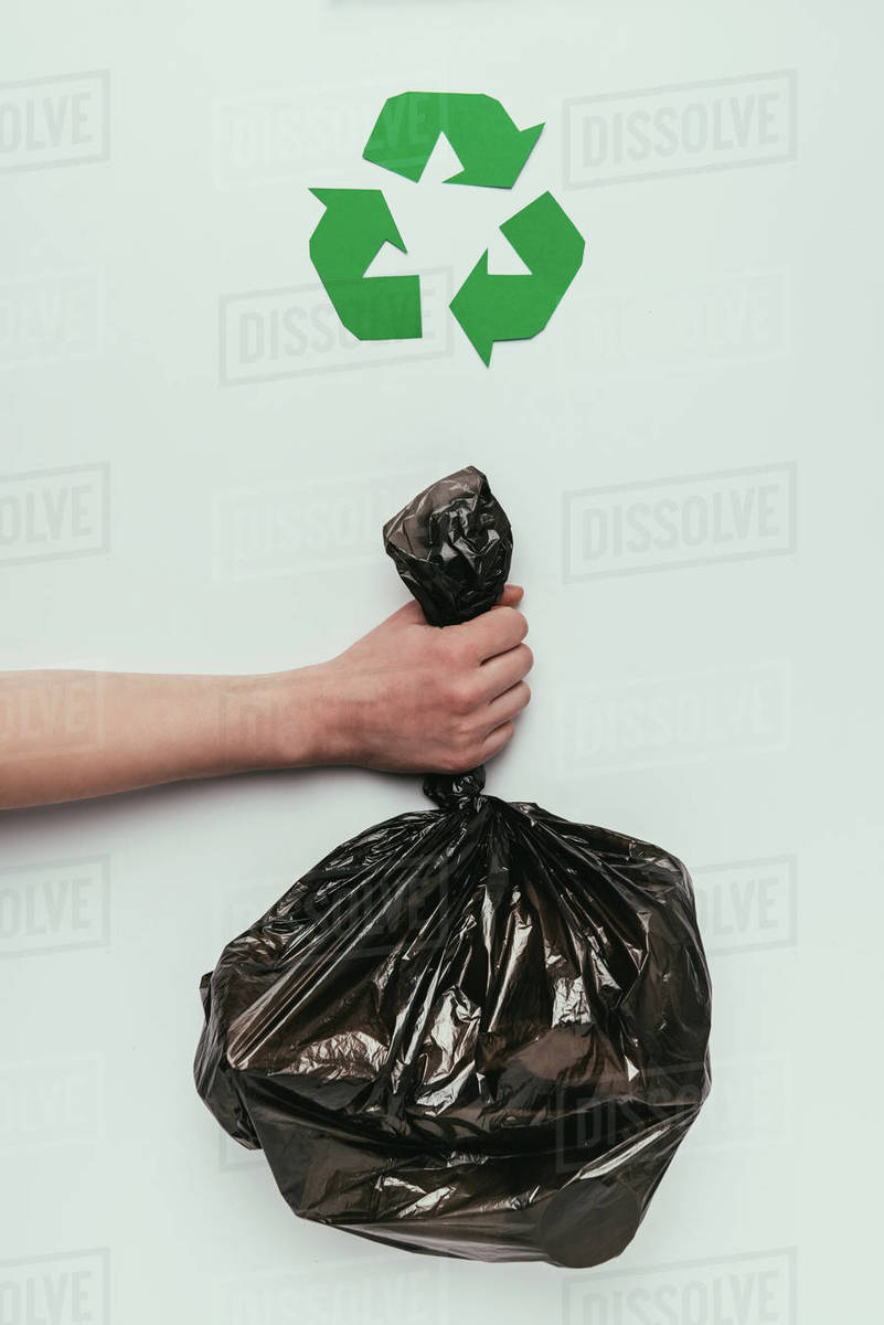 Cropped shot of woman holding garbage bag in hand with recycle sign ...