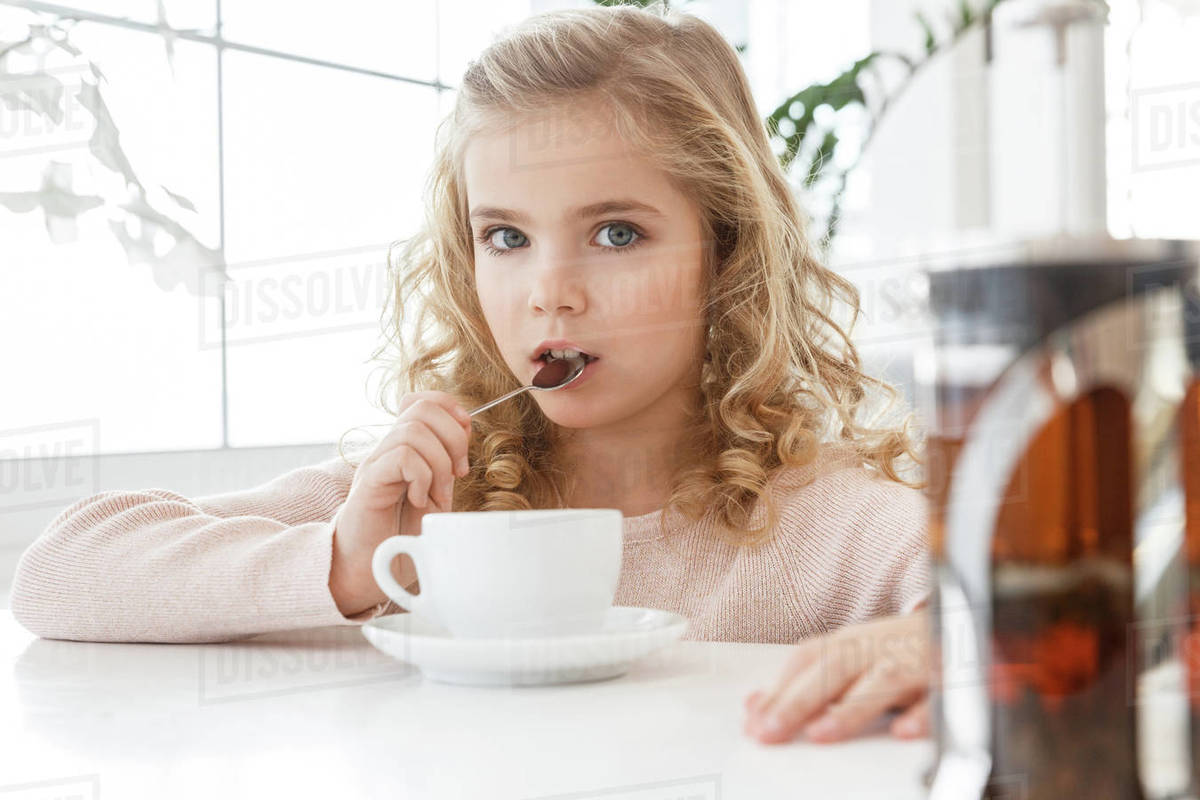 Adorable little child drinking tea in cafe - Stock Photo - Dissolve