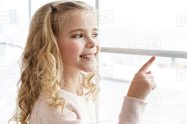 Smiling little child pointing at window - Stock Photo - Dissolve