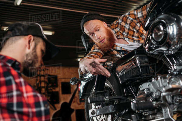 Professional mechanics repairing motorcycle together at garage - Stock ...
