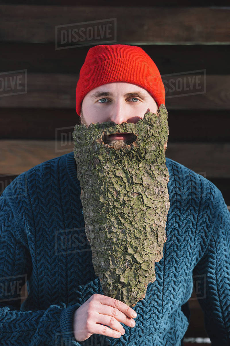 Portrait of man with beard made of wood bark looking at camera outdoors ...