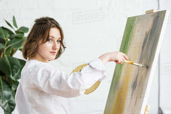 Young inspired girl working by easel in light studio - Royalty-free ...