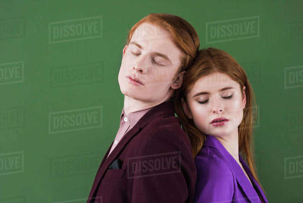 Young fashion models with closed eyes standing back to back isolated on ...