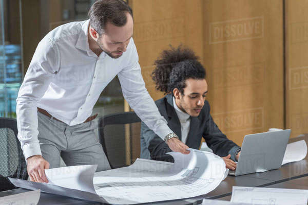 Architects working with building plans together at office - Royalty ...