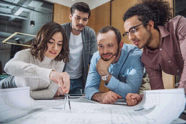 Group of architects drawing building plan together at office - Royalty ...