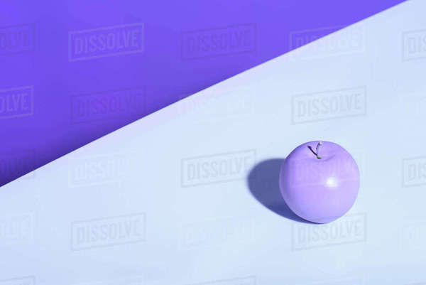 Purple apple on violet background with copy space - Stock Photo - Dissolve