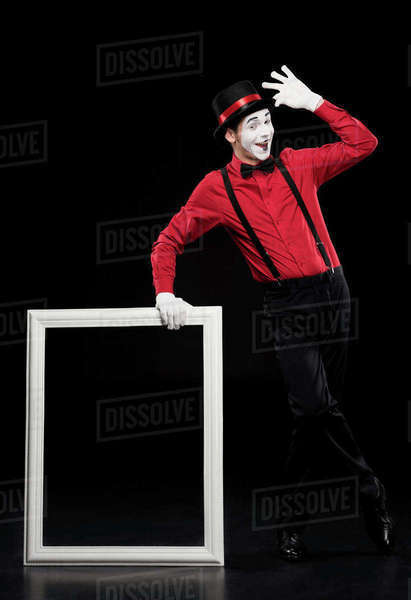 Happy mime leaning on frame and waving hand isolated on black - Royalty ...