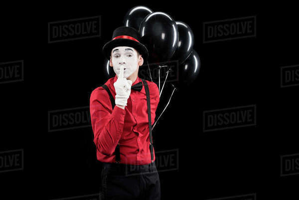 Mime holding balloons and showing silence sign isolated on black ...