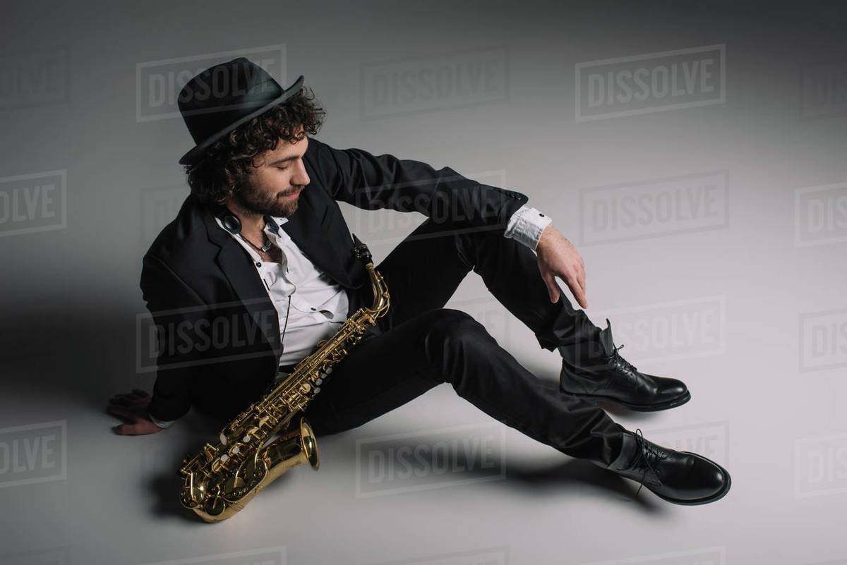 Stylish musician sitting on floor with saxophone - Royalty-free Stock ...