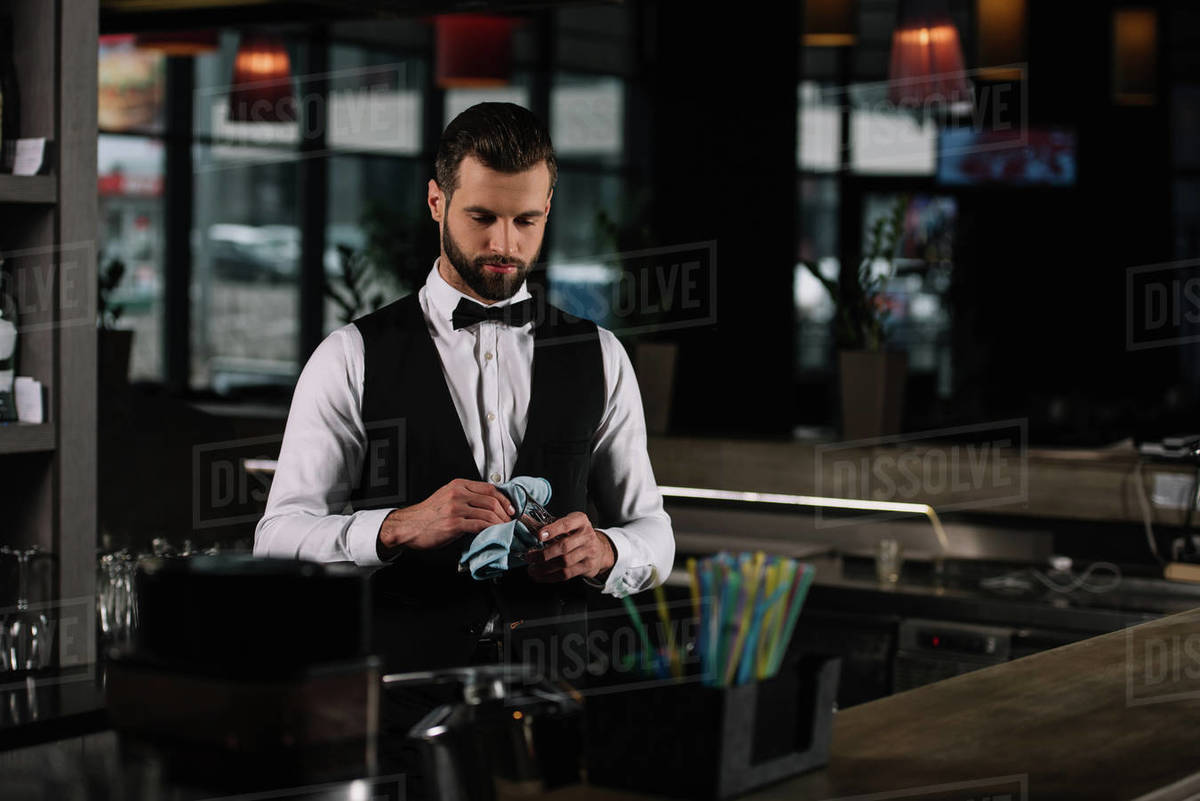 Handsome bartender cleaning glass with rag in evening - Royalty-free ...