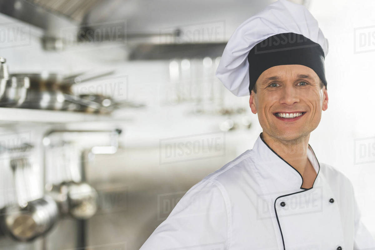 Happy handsome chef looking at camera at restaurant kitchen - Stock ...