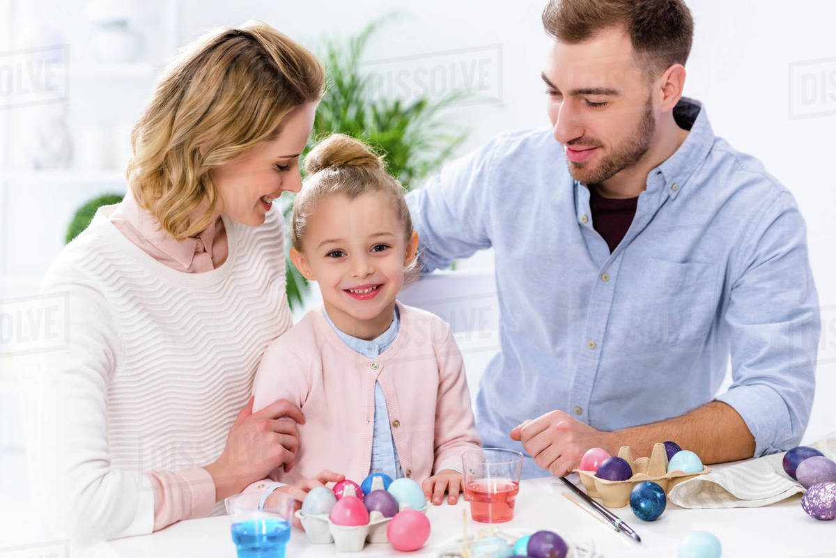 Child and parents by table with easter colored eggs - Royalty-free ...