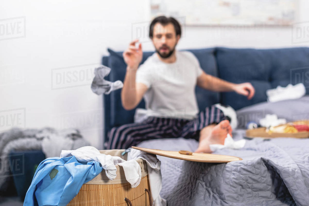 Loner throwing dirty sock into basket with laundry in bedroom - Royalty ...
