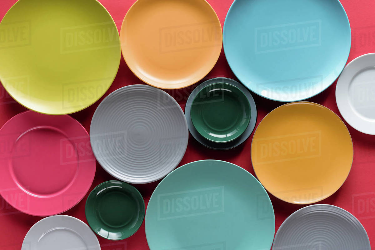 Shiny colorful kitchen ceramic plates on red background - Stock Photo ...