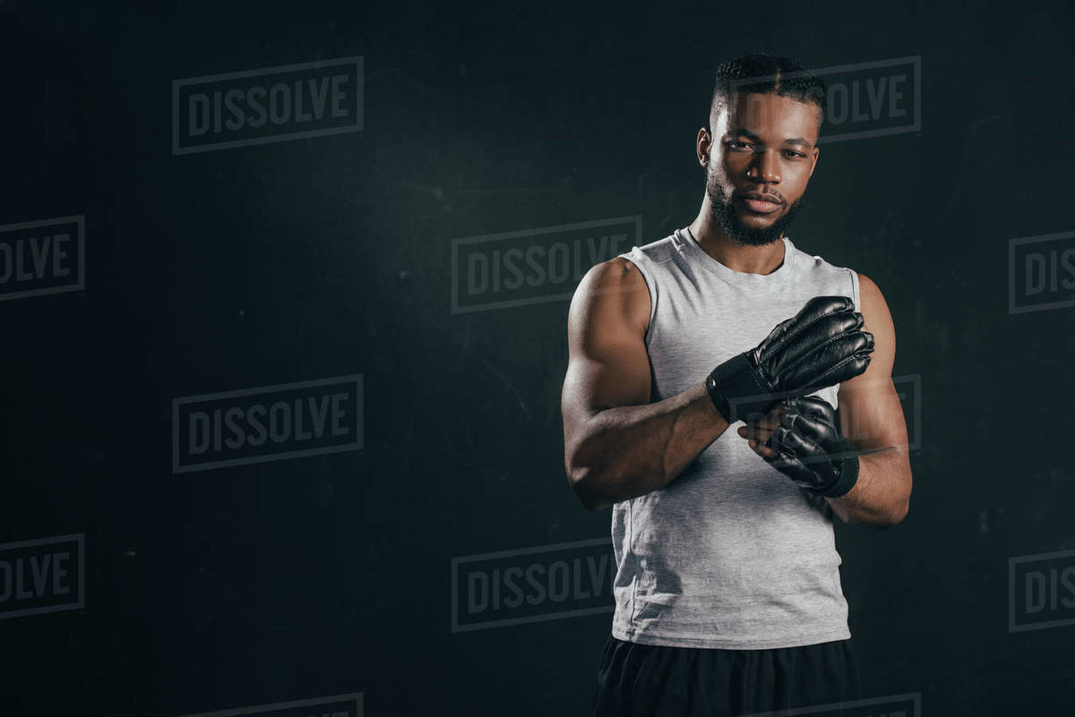 Young African American kickboxer wearing gloves and looking at camera ...