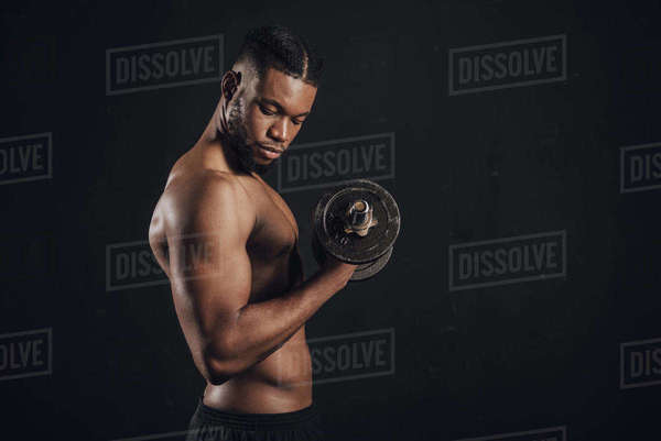 Side view of muscular shirtless African American man exercising with ...