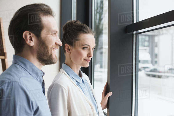 Side view of smiling couple looking out window together - Stock Photo ...