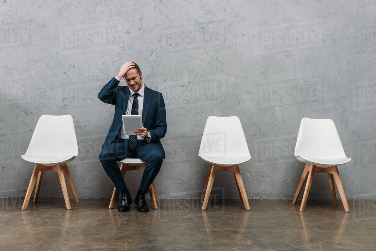 Young frustrated businessman sitting on chair with tablet - Royalty-free Stock Photo | Dissolve