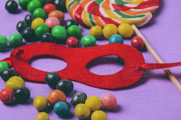 Close up view of candies and masquerade mask isolated on purple - Stock ...