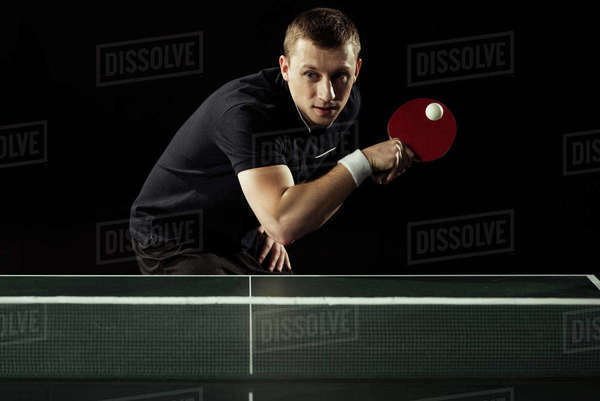 Focused tennis player playing table tennis isolated on black - Royalty ...
