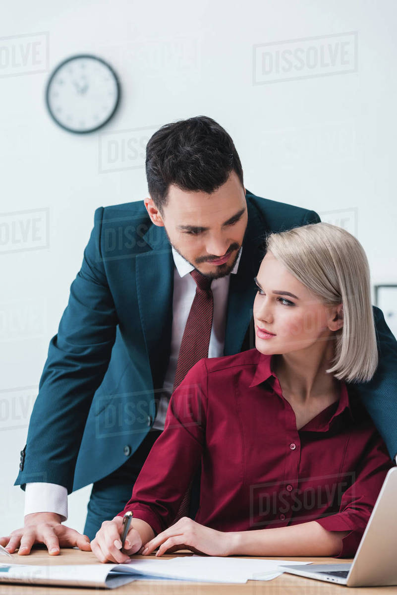 attractive young businessman and businesswoman flirting at workplace ...