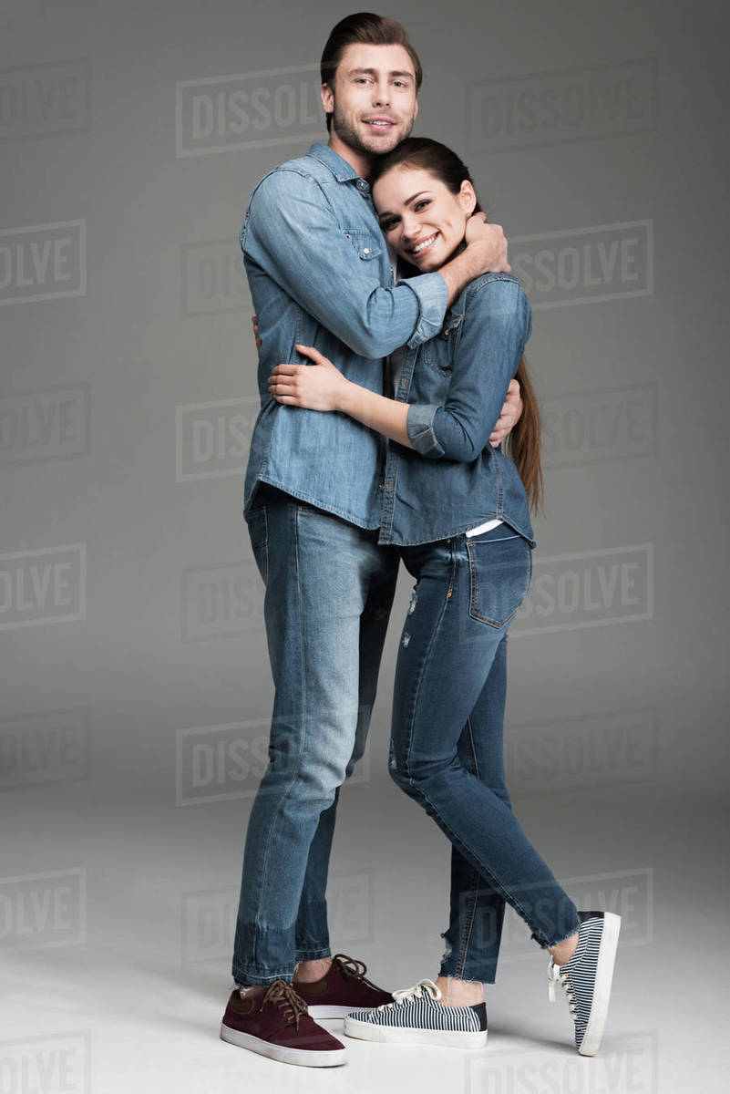 Happy couple hugging and looking at camera, on grey - Stock Photo ...