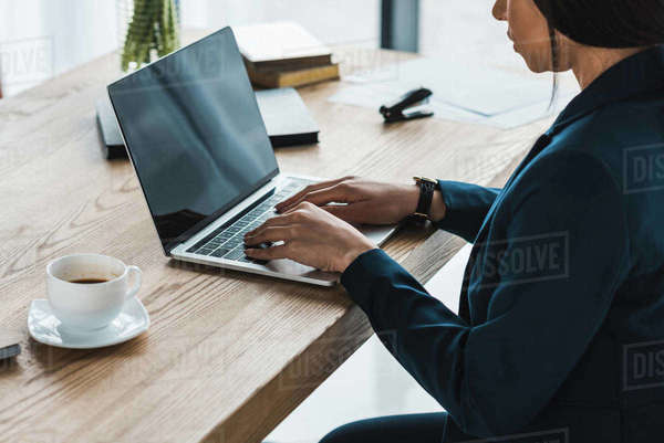 African American businesswoman typing on laptop by table in office ...