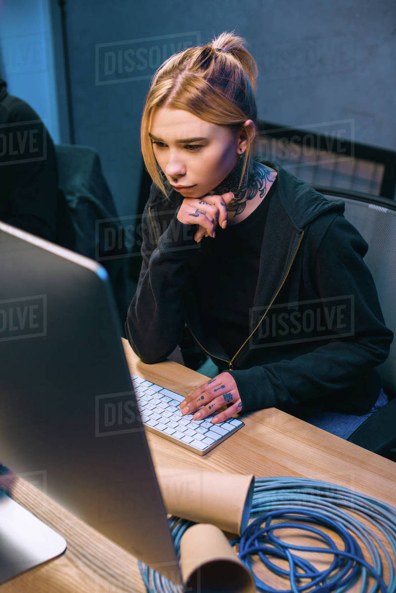Young thoughtful female hacker looking at computer screen - Stock Photo ...