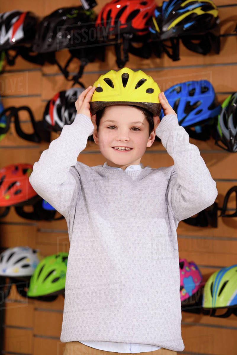 Cute little boy putting on bicycle helmet and smiling at camera in bike ...