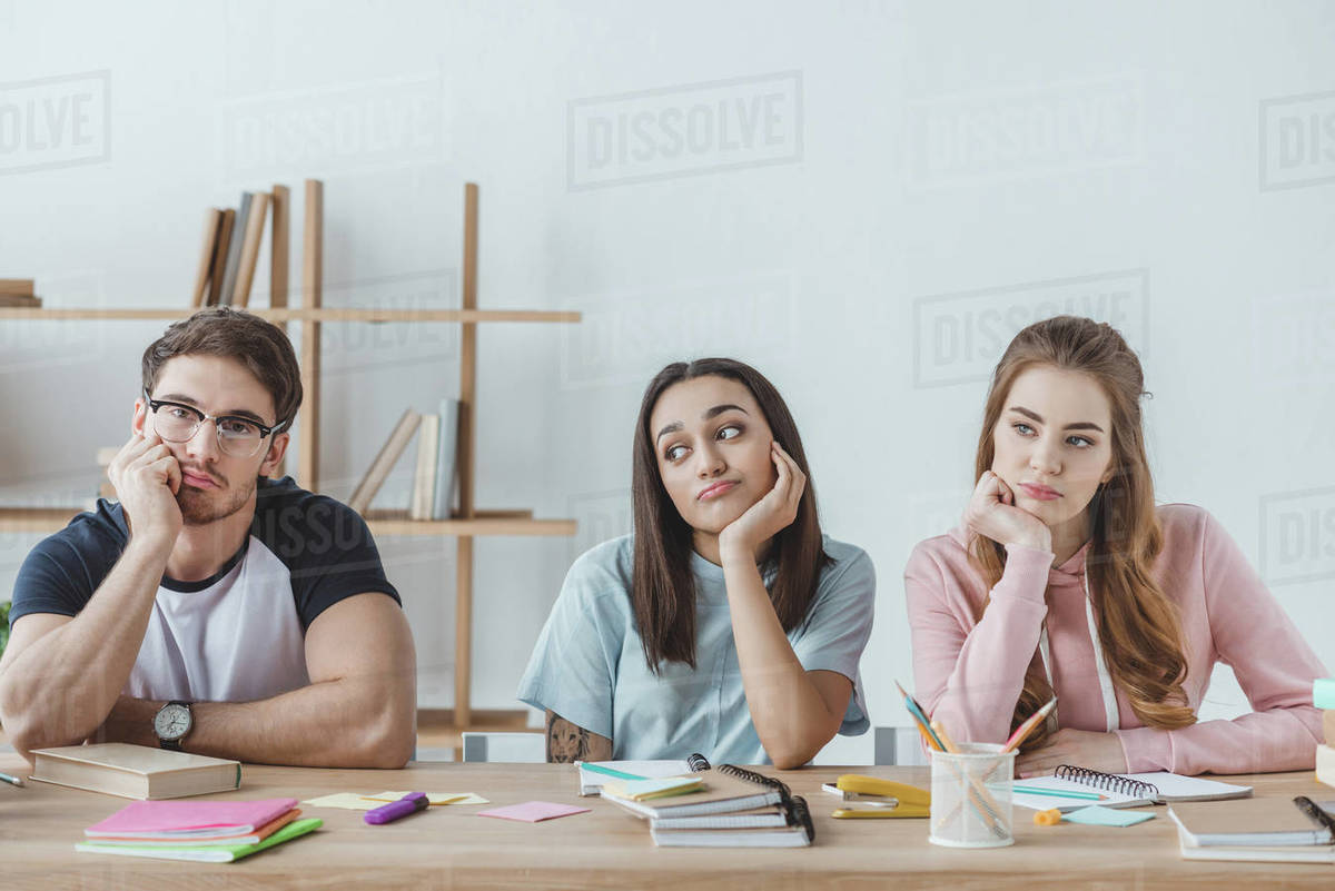 Bored multicultural students sitting at table with books - Royalty-free ...