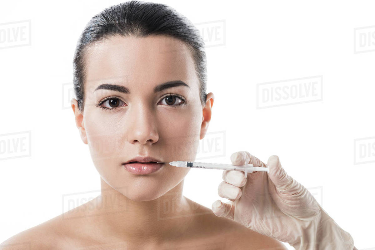 Cropped image of cosmetologist making beauty injection in girls lips ...