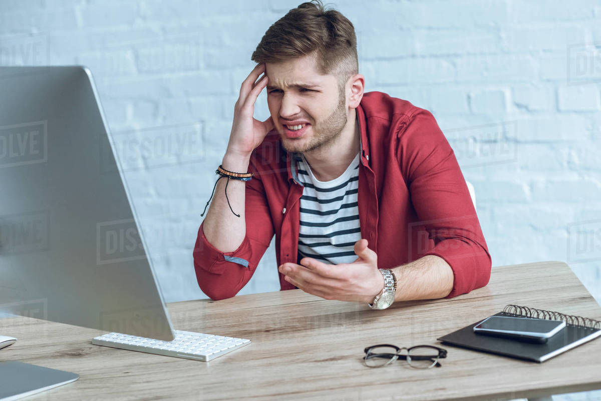 Upset emotional man looking at computer screen - Stock Photo - Dissolve
