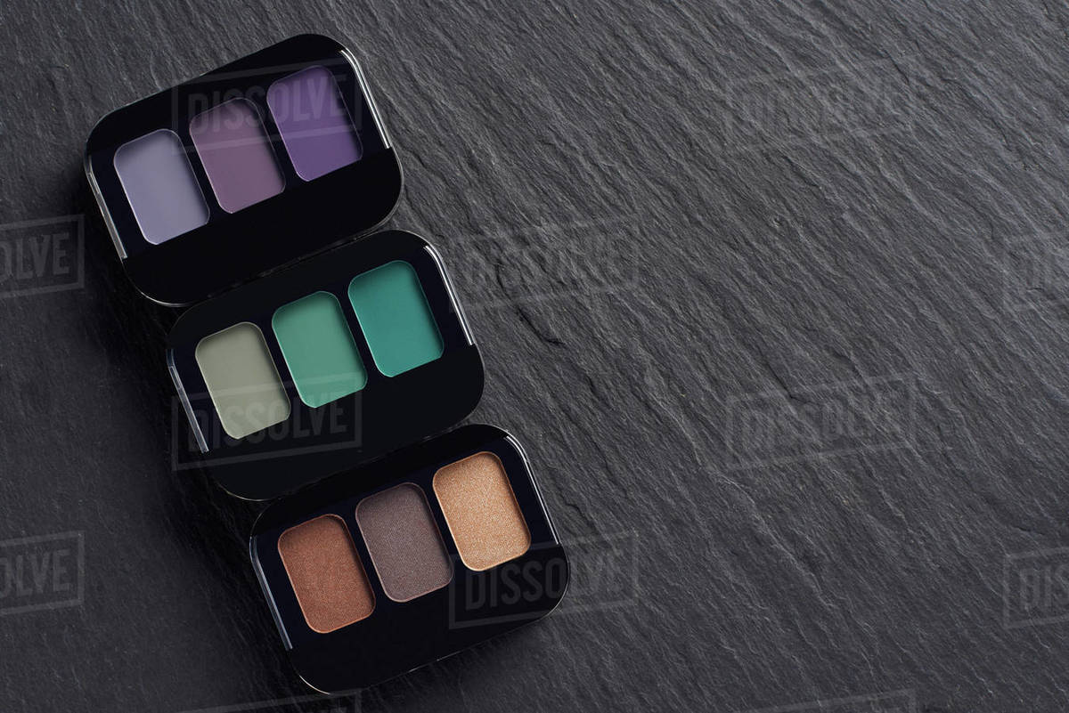 Make up palettes in a row on dark slate background - Stock Photo - Dissolve