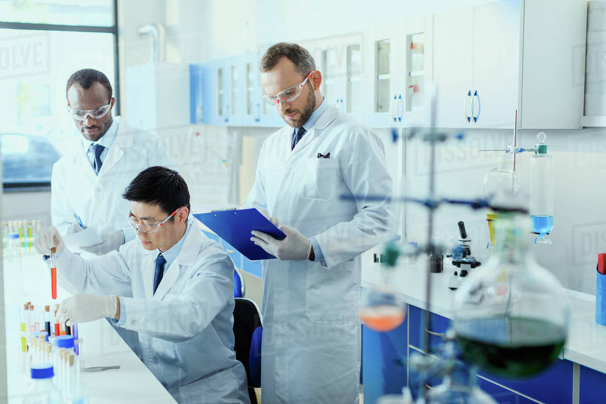Professional scientists in white coats working together in chemical ...