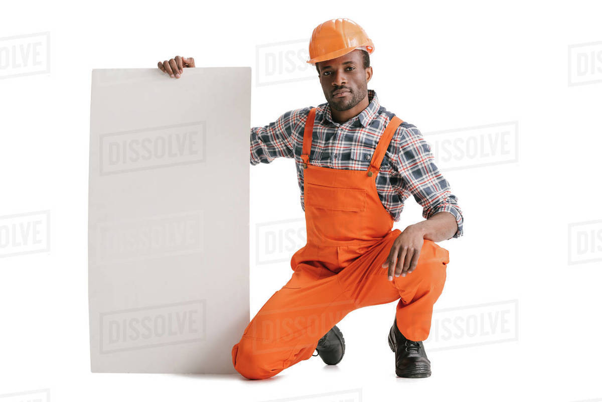 Pensive african-american builder with blank white banner isolated on ...