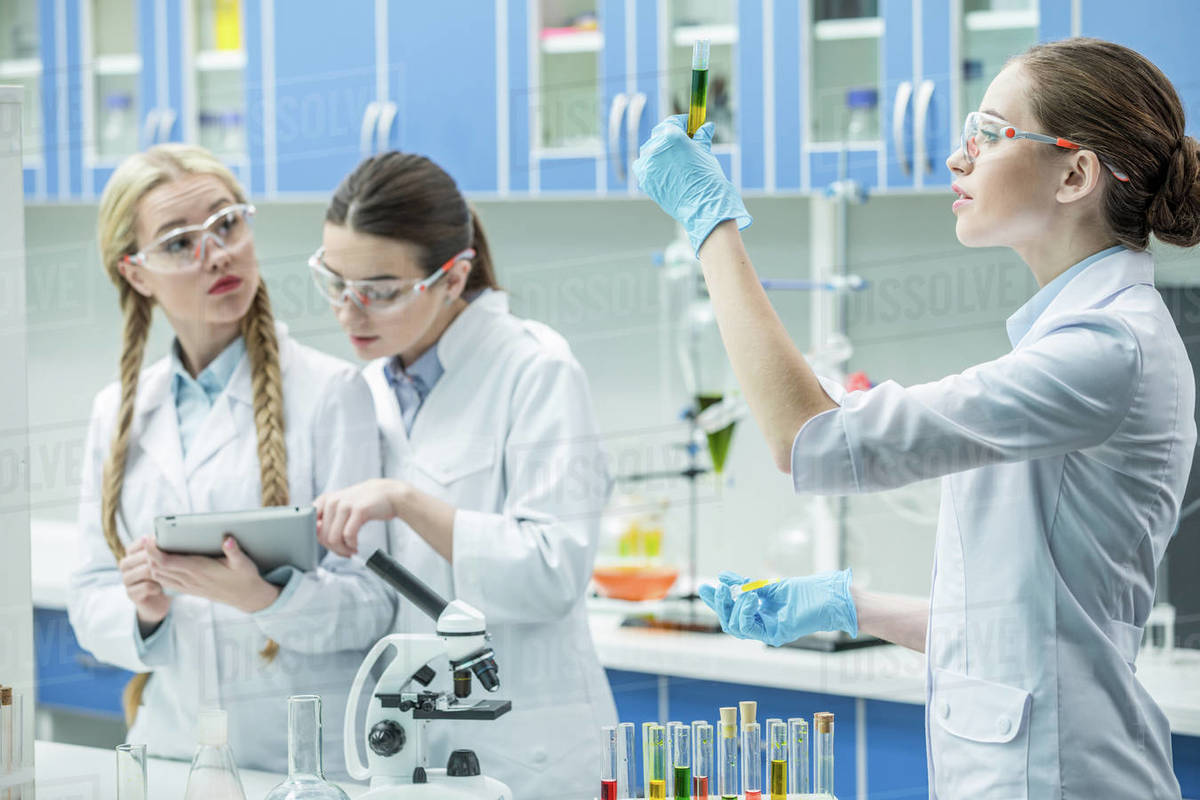 Female scientists working with reagents and digital tablet in chemical ...