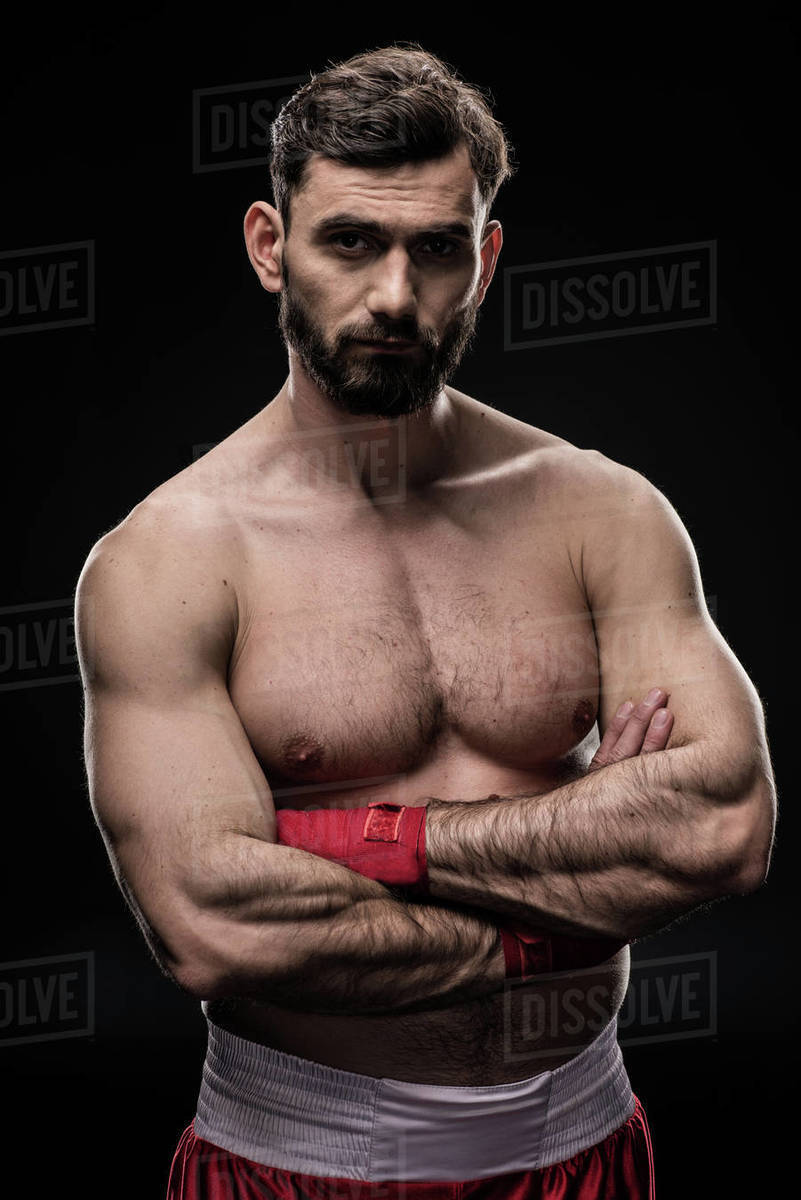 Young muscular boxer with crossed wrapping hands looking at camera ...