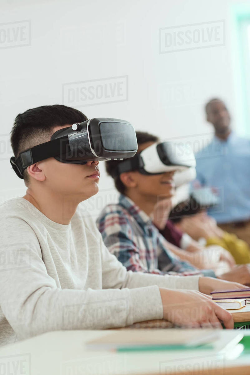 Side view of multiethnic high school pupils using virtual reality ...