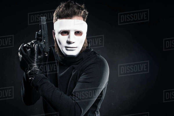 Criminal in white mask and black clothes holding gun - Royalty-free ...
