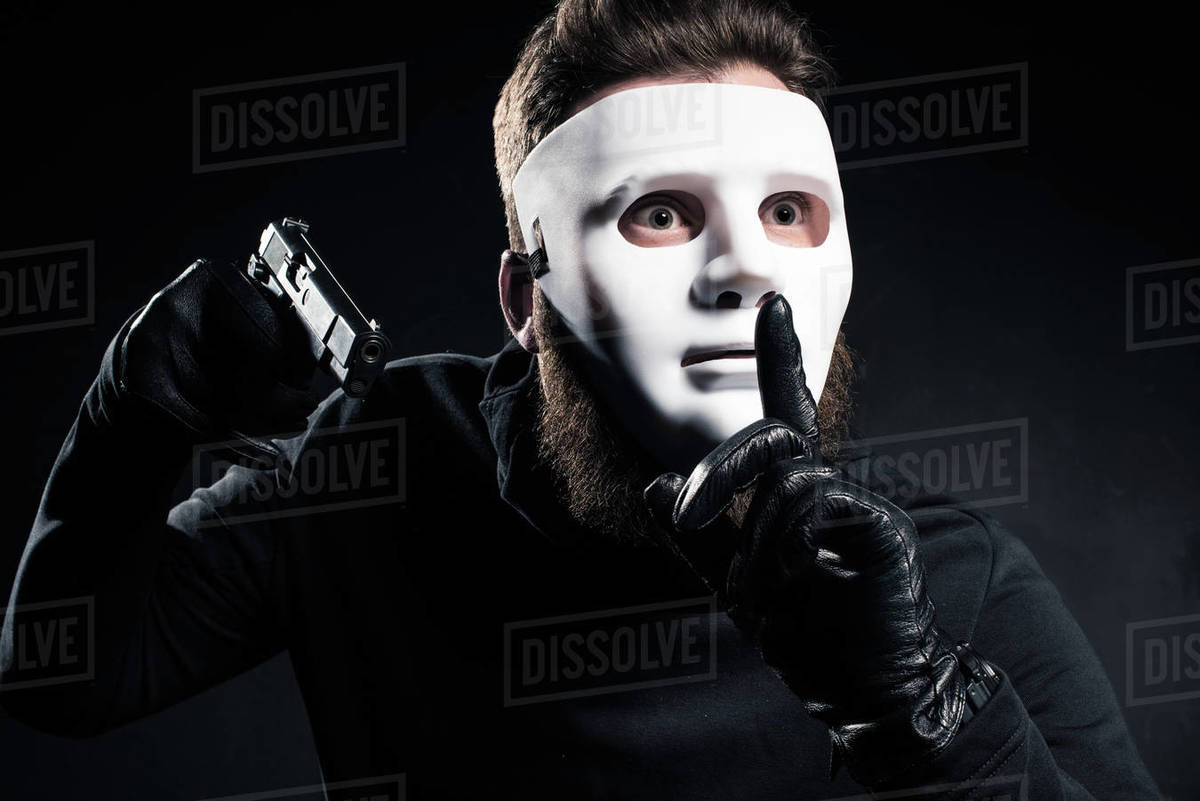 Robber in mask holding gun and showing silence gesture - Stock Photo ...